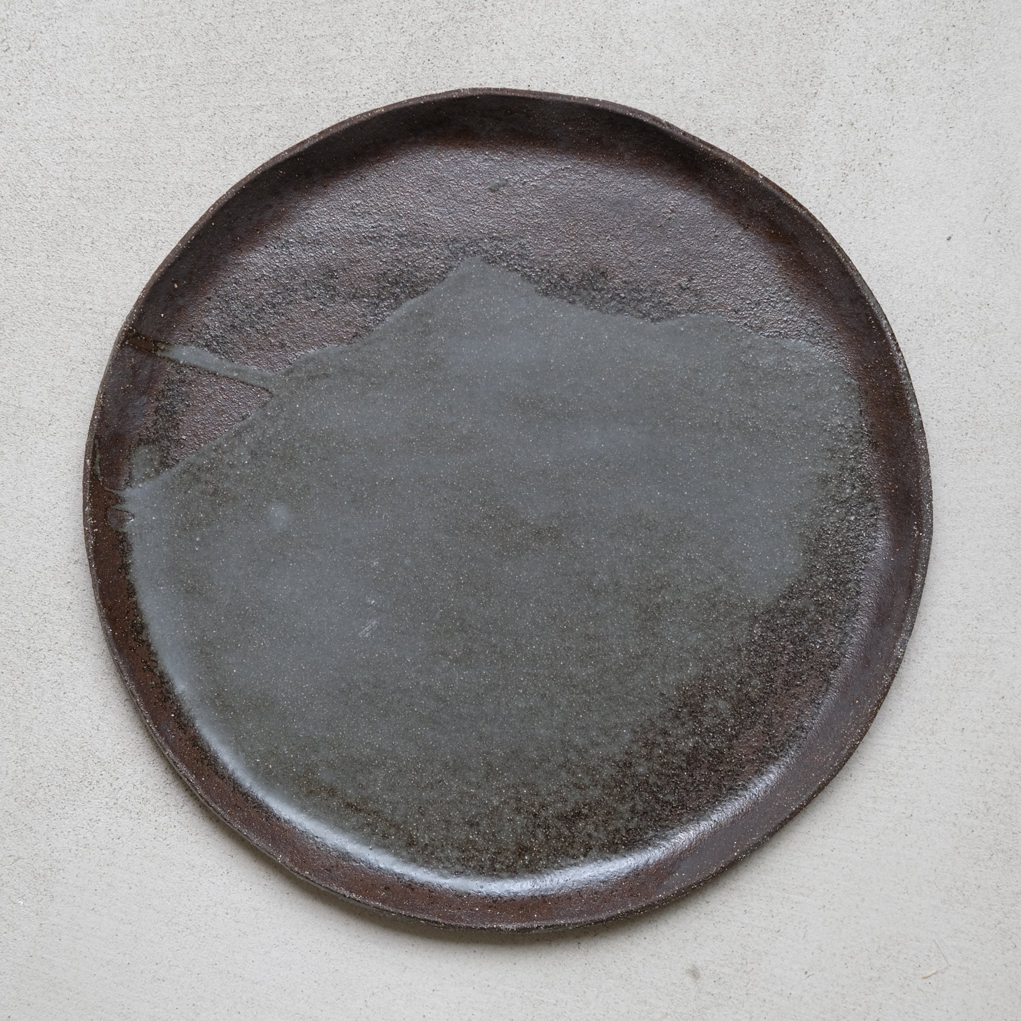 Assiette en grès noir moucheté d'Elsa Haas chez Brutal Ceramics